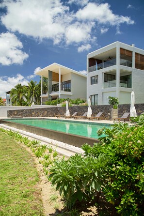 Um hotel moderno com piscina, espreguiçadeiras e vista para o oceano.