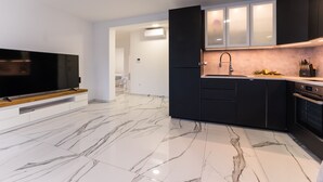 Uma cozinha moderna com televisão de tela plana, armários pretos e chão de mármore.