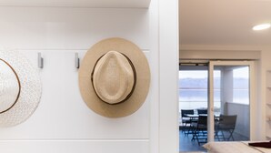 Quarto com cama, área de jantar com cadeiras e dois chapéus pendurados na parede.