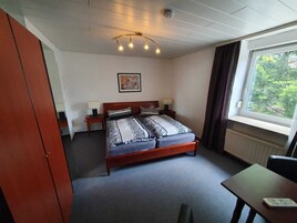 Um quarto com cama, mesas de cabeceira, janela com vista e luminária no teto.