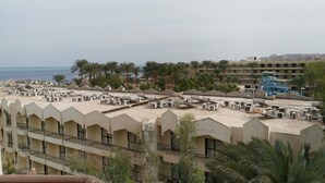 Um hotel com vários andares, unidades de ar condicionado no telhado e vista para o mar.