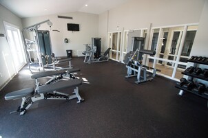 Uma academia com diversos equipamentos de exercícios, incluindo bancos e aparelhos de musculação.
