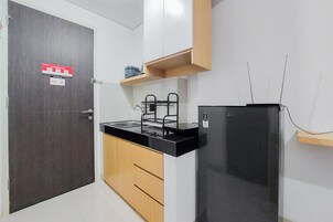 Uma cozinha compacta com uma porta de madeira escura, uma geladeira preta, bancada com pia e um armário de madeira.