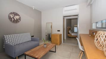 Uma sala de estar moderna com um sofá, uma mesa de centro de madeira, um espelho e uma área de jantar com mesa e cadeiras.