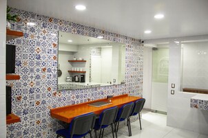 Cozinha moderna com azulejos estampados, bancada de madeira e banquetas.