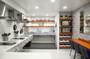 Uma cozinha moderna com uma ilha central, forno embutido e micro-ondas. Há prateleiras acima da ilha com utensílios de cozinha e um espaço de bar com banquetas.