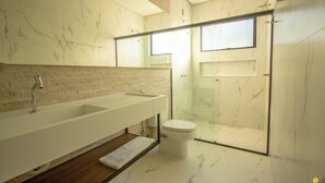 Casa de banho moderna com uma grande pia, sanita e cabine de duche em vidro.