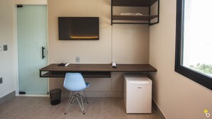 Um espaço de escritório moderno com uma mesa, cadeira e um pequeno frigorífico branco.
