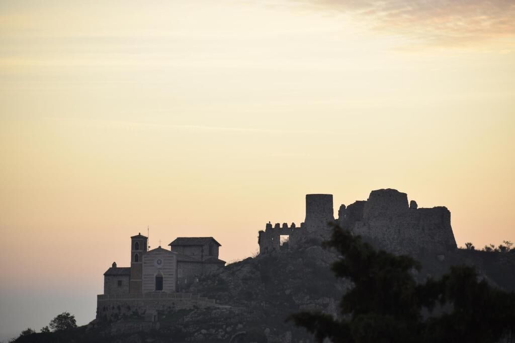 Um edifício histórico com uma torre imponente e uma estrutura fortificada numa colina.