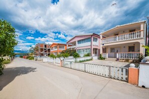 Rua residencial com casas, céu claro e montanha ao longe.