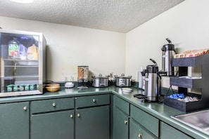 Uma cozinha compacta equipada com geladeira, cafeteira e diversas panelas.