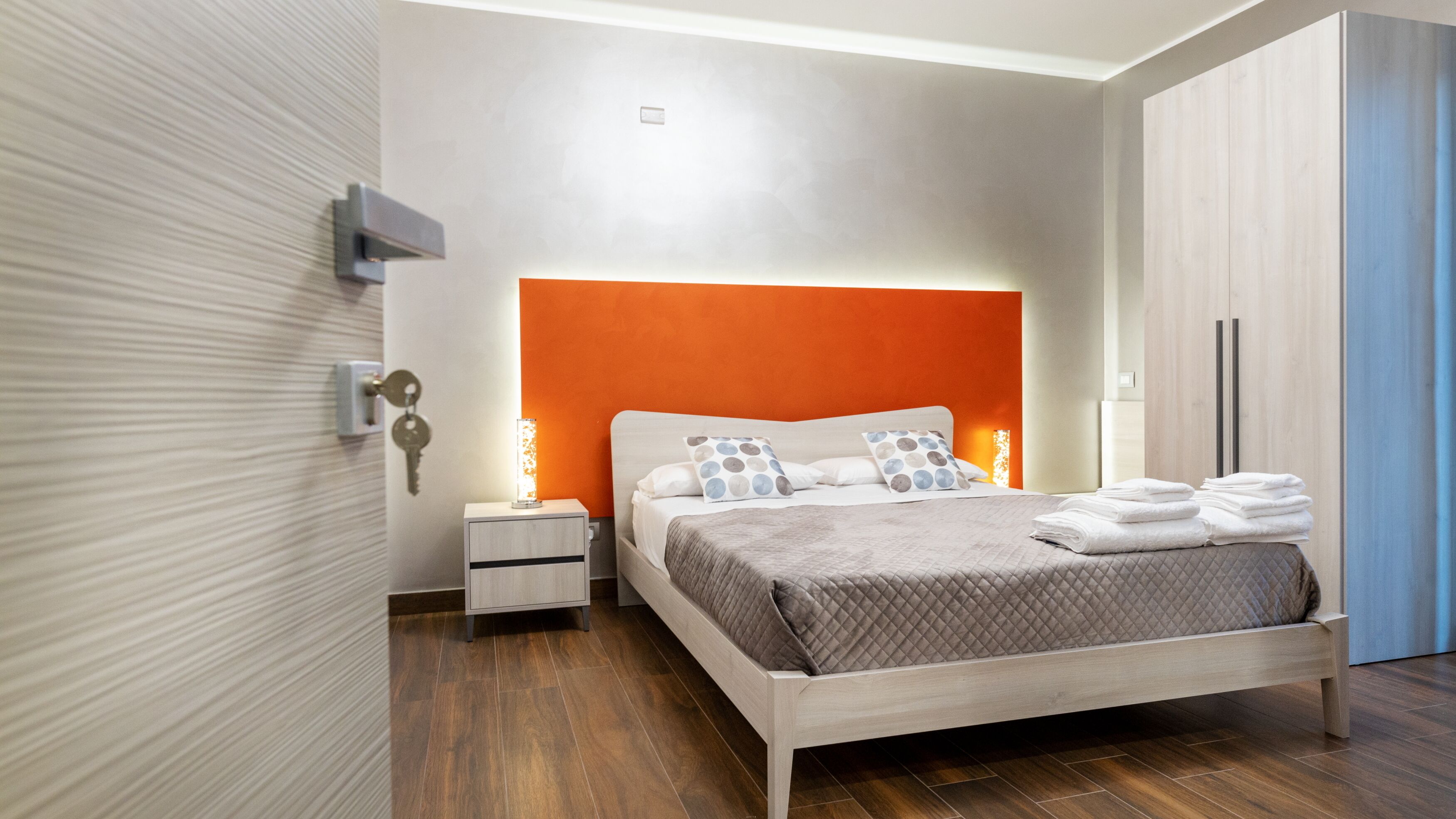 Quarto moderno com cama, mesas de cabeceira e guarda-roupa.