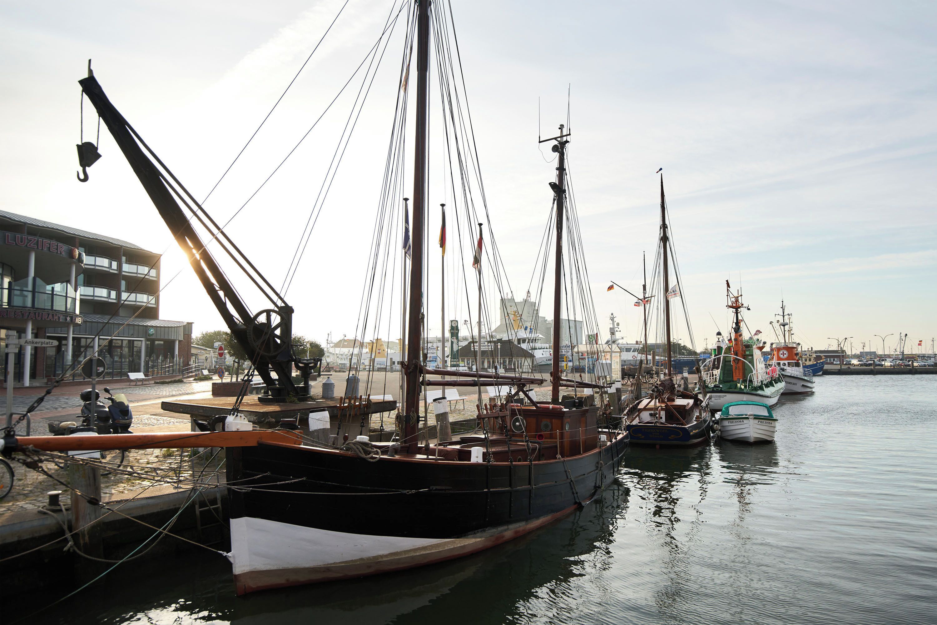 Marina com vários barcos atracados, uma grua e um edifício com o letreiro "RESTAURANT".