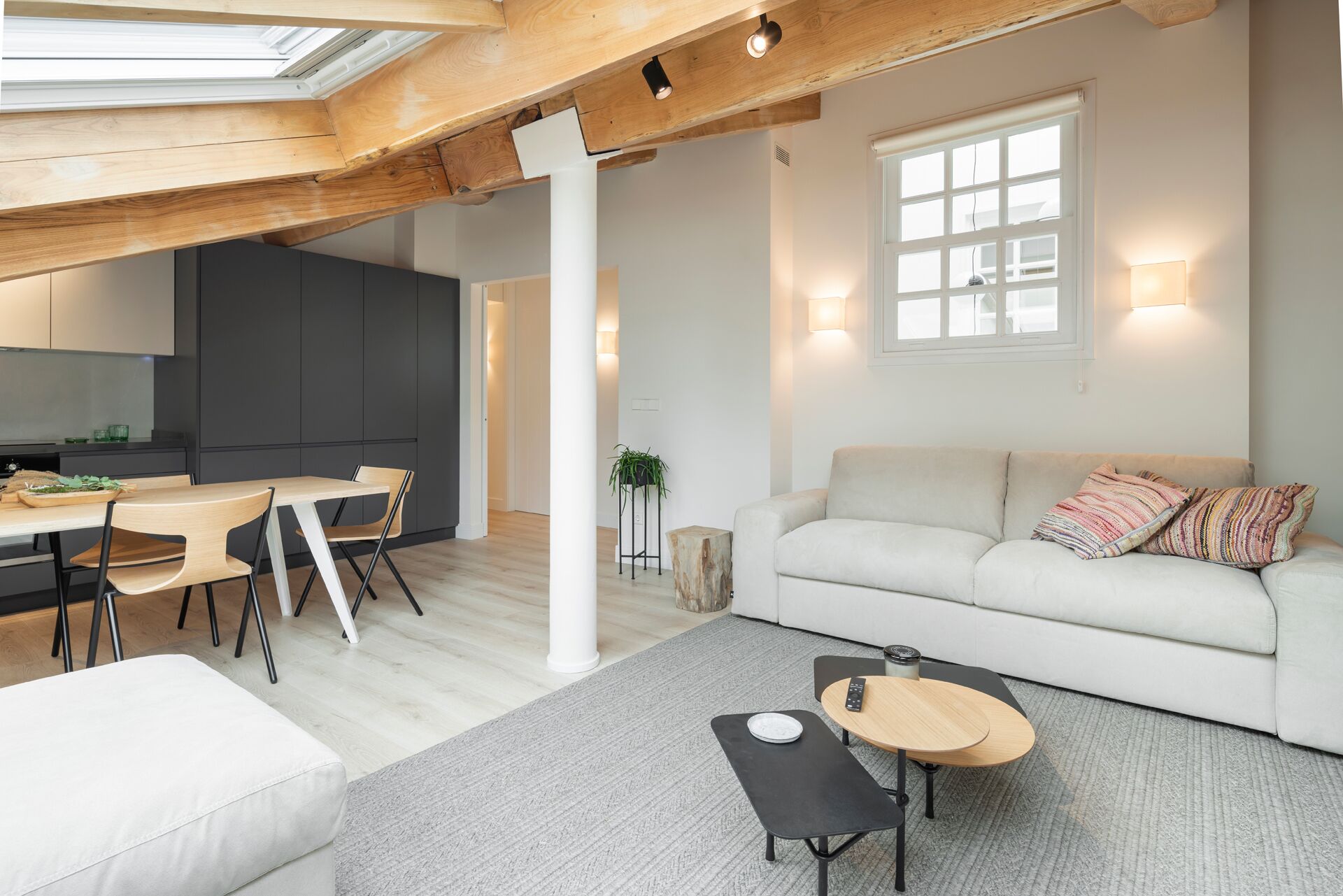 Um espaço de estar moderno com área de jantar, sofá e mesa de centro.