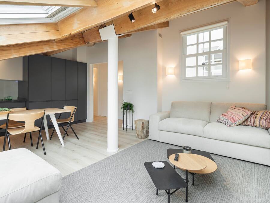 Um espaço de estar moderno com área de jantar, sofá e mesa de centro.