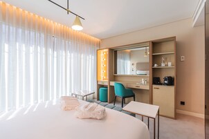 Quarto de hotel moderno com uma cama grande, uma escrivaninha, uma cadeira e uma toucador com espelho.
