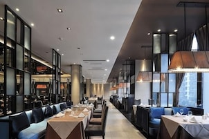 Um restaurante moderno com mesas compridas e cabines, tetos altos e janelas amplas.