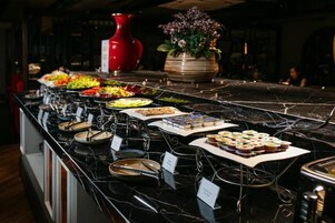 Buffet com diversos alimentos e um vaso de flores no balcão.