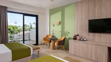 Quarto de hotel com duas camas, televisão, mesa com cafeteira e varanda com mesa e cadeiras.