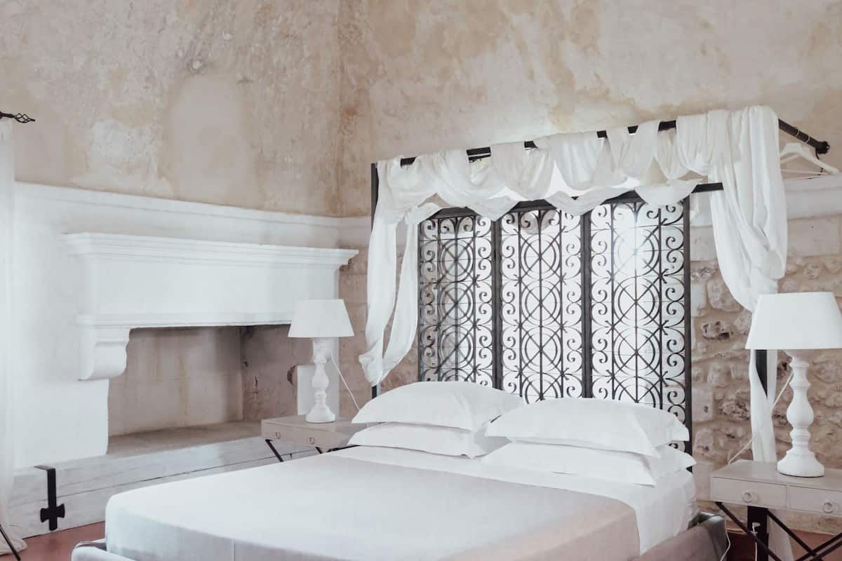 Quarto com uma cama grande, lareira e cabeceira de metal decorativa.