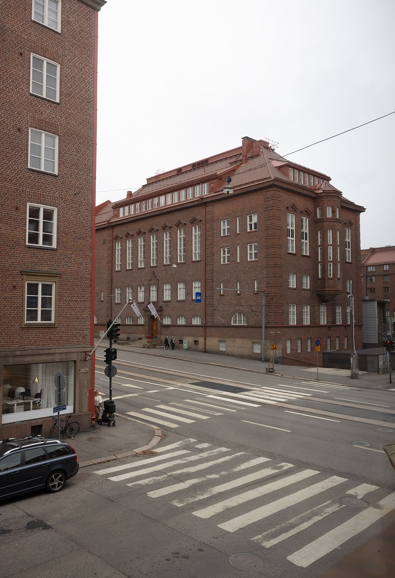 Um grande edifício de tijolos com várias janelas e uma faixa de pedestres em frente.