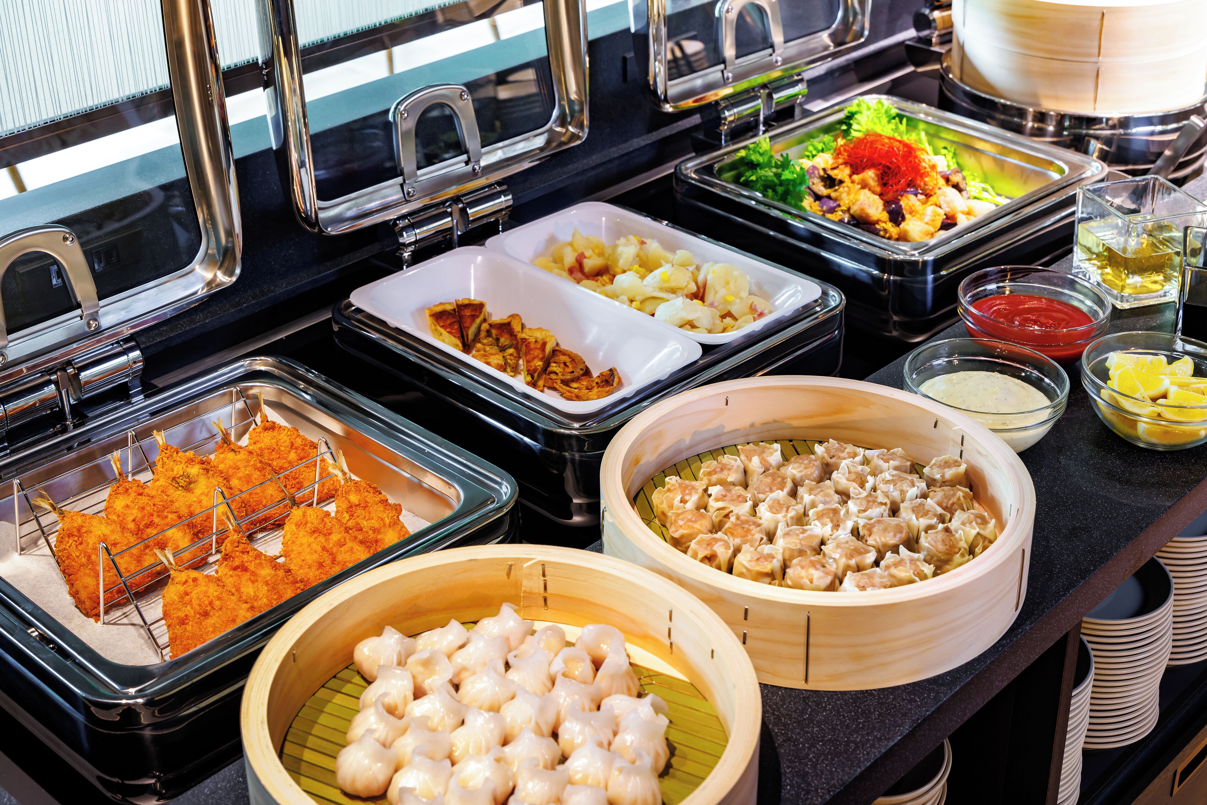 Buffet com diversos alimentos, incluindo frituras, pasteizinhos e saladas.