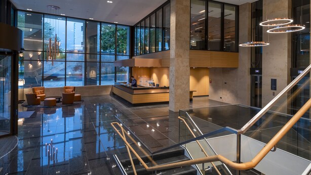 Um lobby moderno com balcão de atendimento, área de estar e escada.