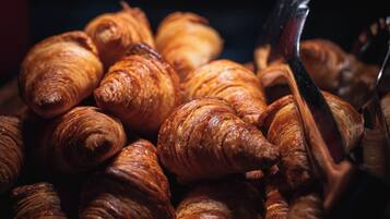 Close-up de uma bandeja de madeira repleta de croissants dourados.