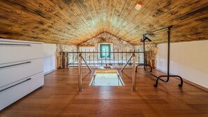 Um quarto amplo no sótão, com vigas de madeira, uma parede de pedra e vista para uma porta verde.