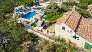 Uma villa com piscina, área de estar externa e um edifício de pedra com telhado de cerâmica.