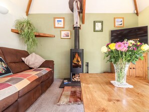 Uma sala de estar aconchegante com um sofá de couro marrom, uma mesa de madeira com um vaso de flores, uma lareira e quadros nas paredes.