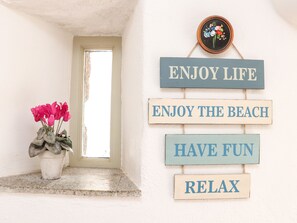 Uma parede com placas motivacionais dizendo "ENJOY LIFE", "ENJOY THE BEACH", "HAVE FUN" e "RELAX".