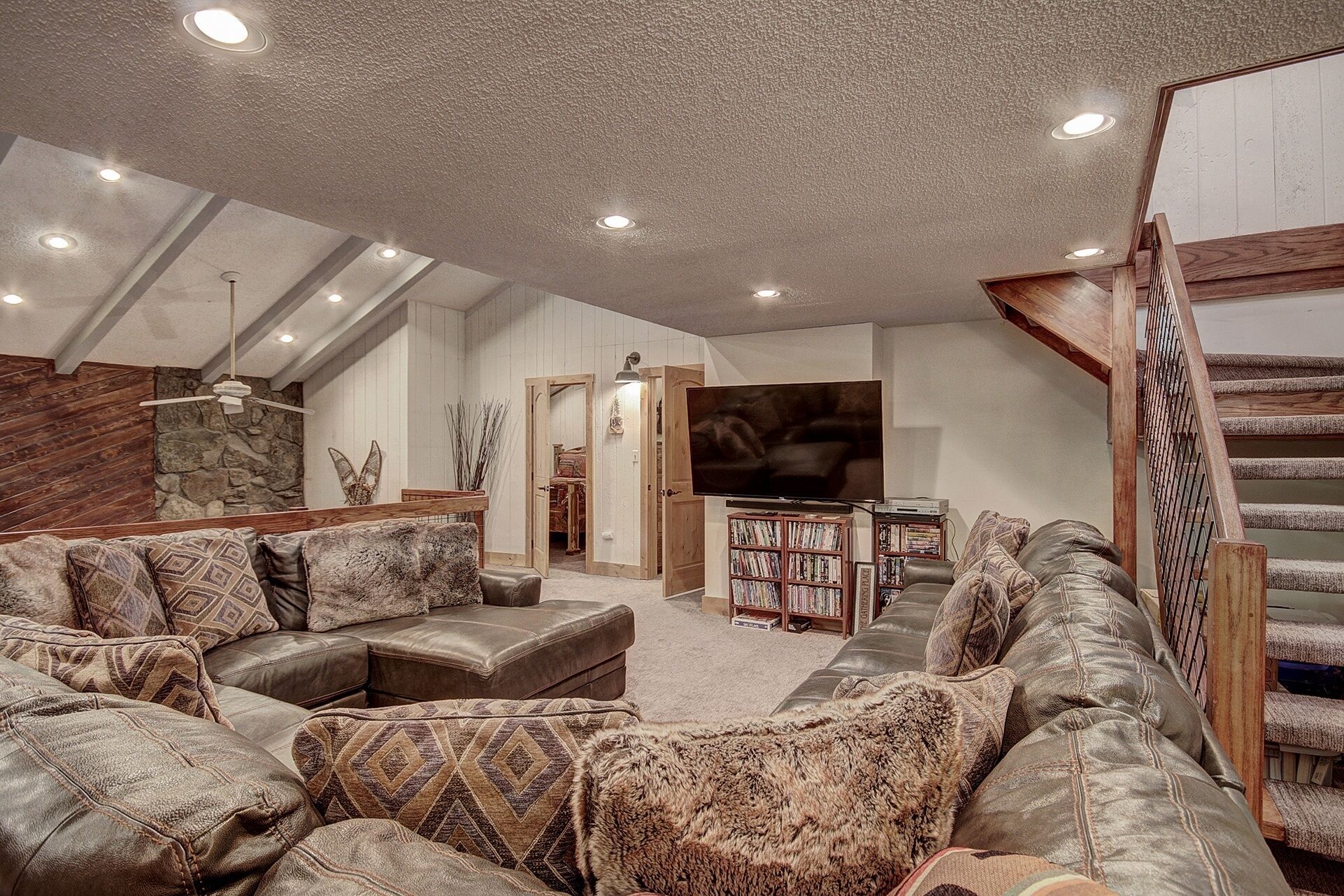 Uma sala de estar ampla com sofás de couro, uma televisão e uma estante de livros.