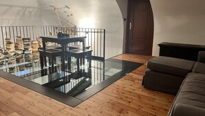 Um loft moderno com mesa de jantar de vidro, piso de madeira e uma área de estar aconchegante.