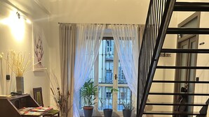 Uma sala de estar espaçosa com piso de madeira, uma mesa de jantar e uma escada.
