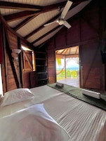 Quarto com cama, ventilador de teto e vista para o exterior.