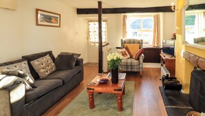 Uma sala de estar aconchegante com um sofá cinza escuro, uma poltrona xadrez e uma mesa de centro de madeira com um vaso de flores.