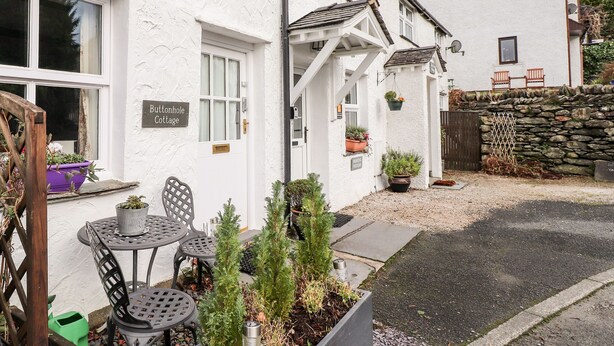 Uma casa de campo branca com uma placa que diz 'Buttonhole Cottage'.