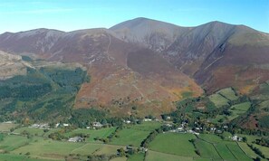 Paisagem rural com uma aldeia situada em vales e rodeada por montanhas.