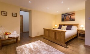 Quarto com cama de madeira, abajures, tapete fofo e um quadro na parede.