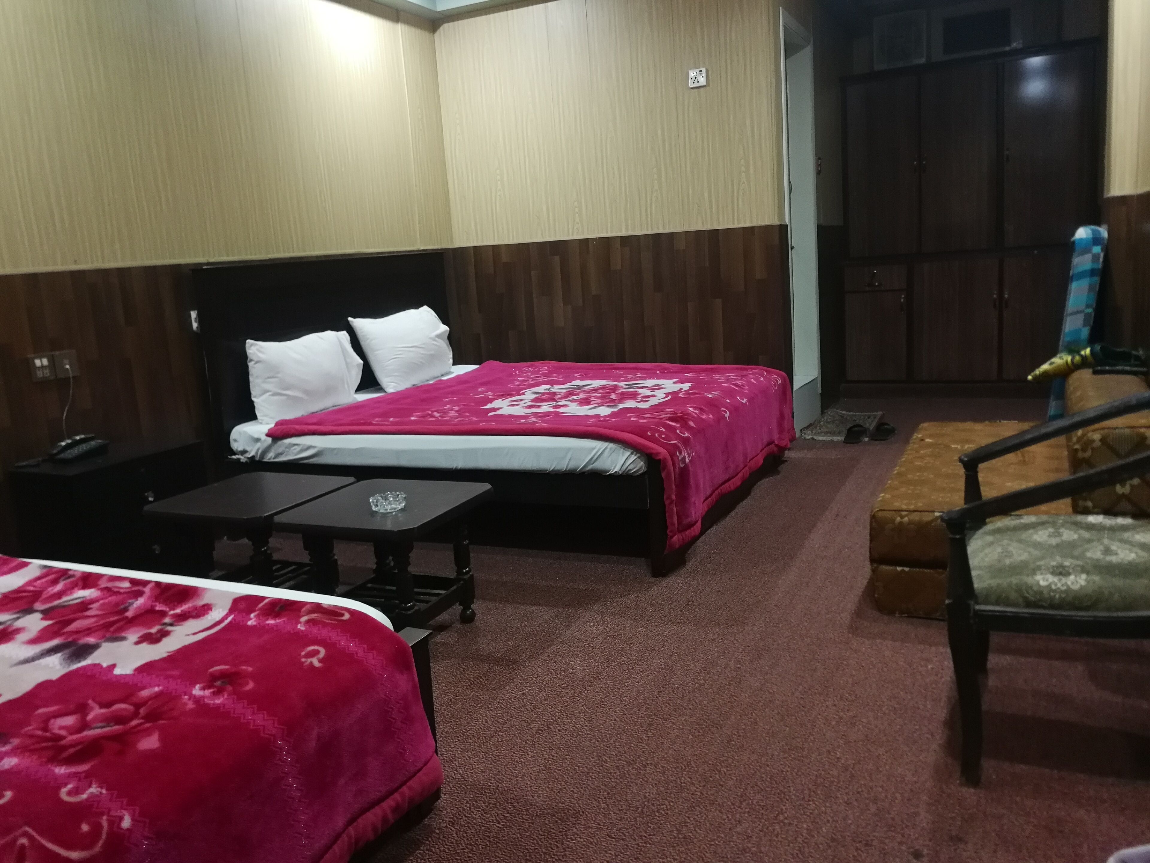 Quarto de hotel com cama, uma pequena mesa, uma cadeira e um guarda-roupa.