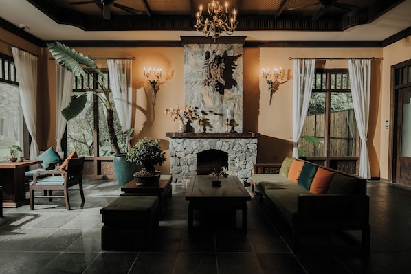 Uma sala de estar aconchegante com lareira de pedra, assentos confortáveis e uma planta grande.