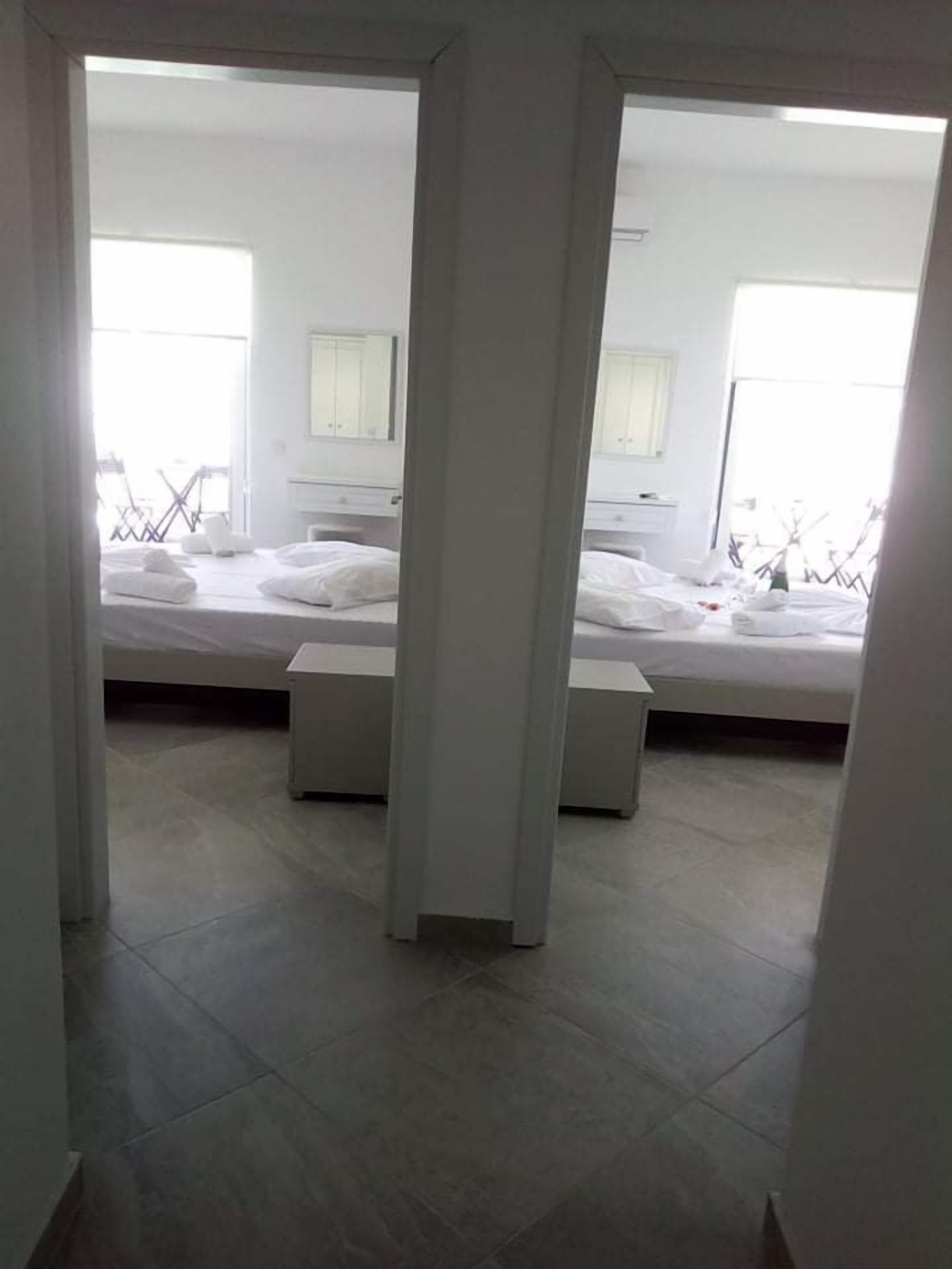 Quarto de hotel moderno com uma cama grande, uma mesinha de cabeceira e janela com vista para o exterior.