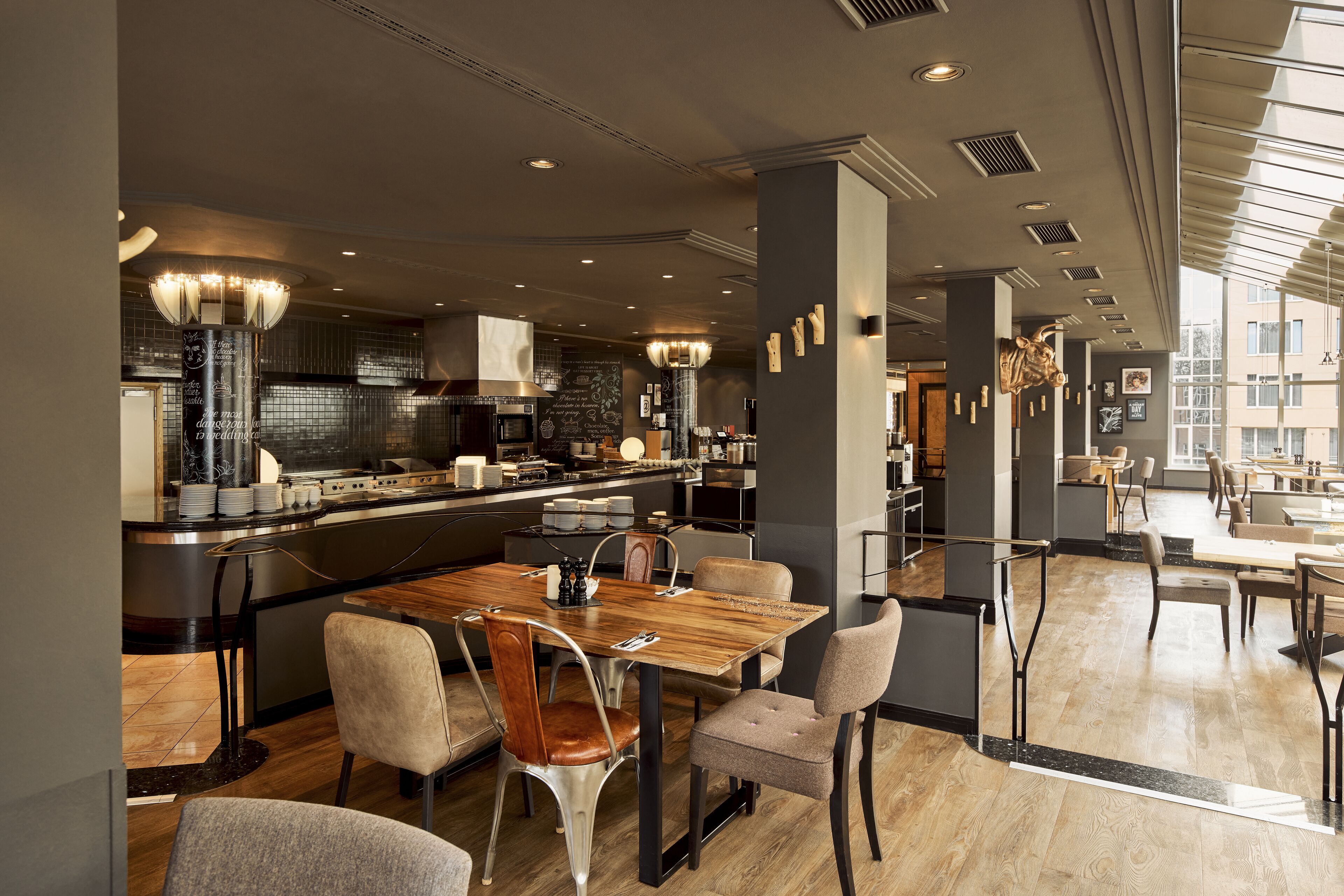 Um restaurante moderno com uma ilha central, pé direito alto e uma variedade de áreas de estar.