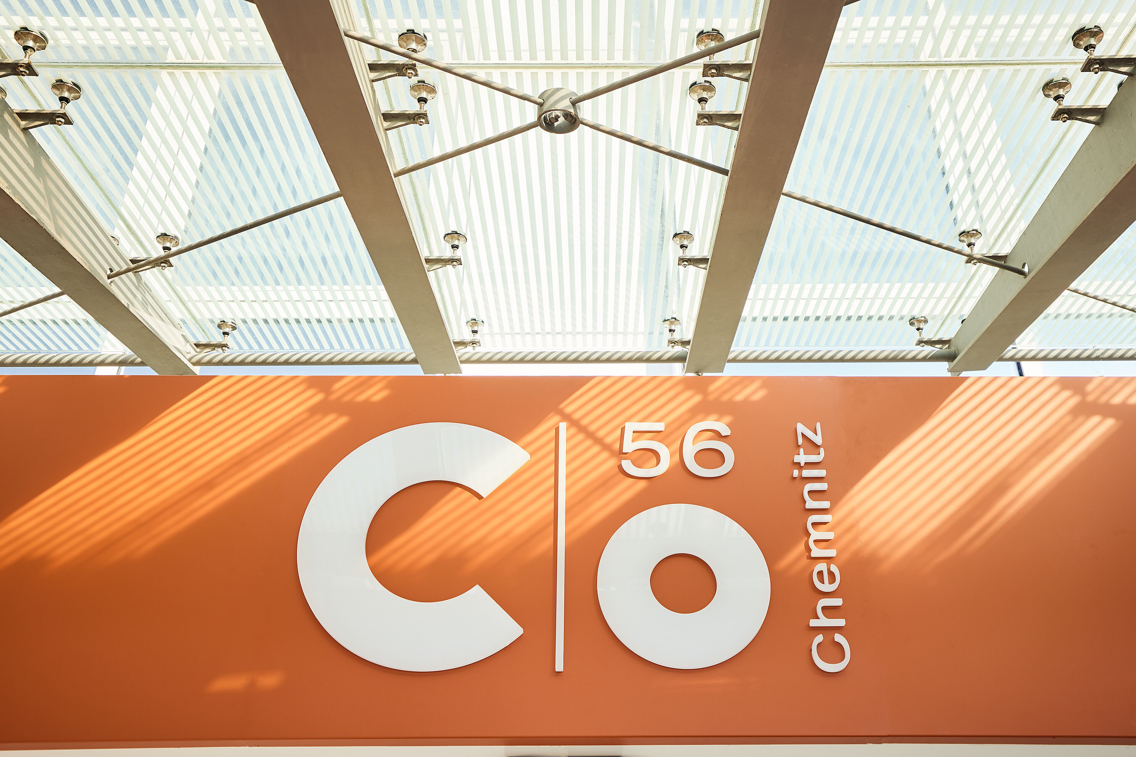 Um letreiro com o texto 'Clo 56 Chemnitz' sob uma estrutura de teto de vidro.