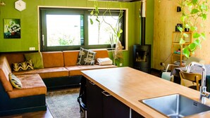 Uma cozinha moderna com bancada de madeira e armários pretos, fogão embutido e parede verde.