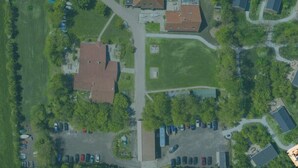 Vista aérea de um terreno com vários edifícios, um estacionamento e um corpo d'água.