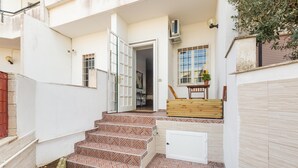 Um edifício residencial com uma escadaria de azulejos que leva a uma porta de madeira.