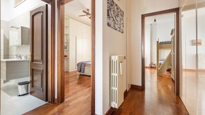 Corredor com piso de madeira, radiador e escada que dá acesso a outro cômodo.