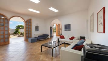 Uma sala de estar espaçosa com design moderno, destacando uma mesa de centro grande, dois sofás e um toca-discos.